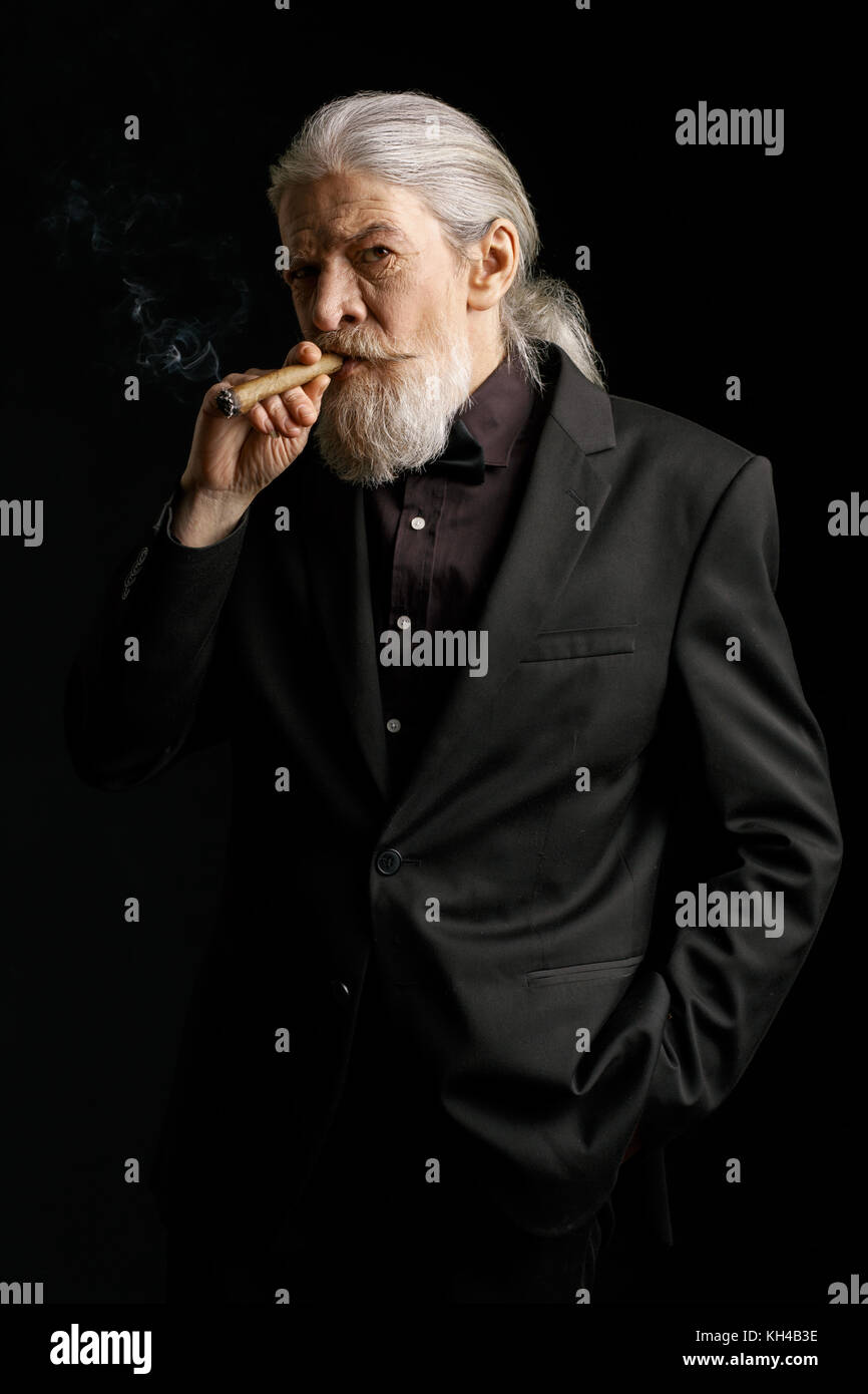 Aged wrinkled man standing against black background Stock Photo - Alamy