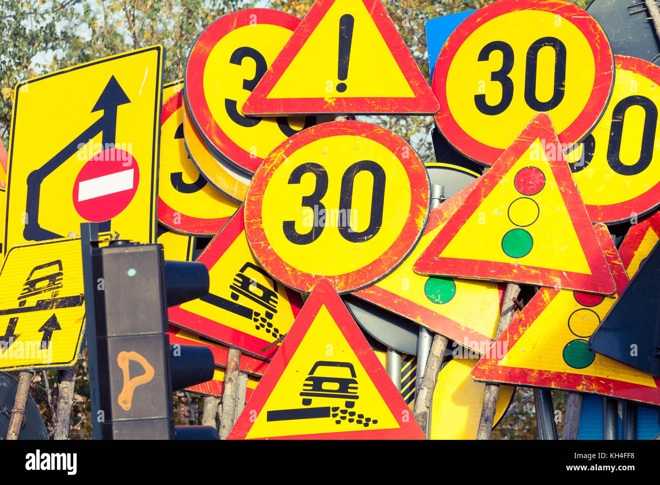 Many industrial road signs and old traffic lights stacked together as ...