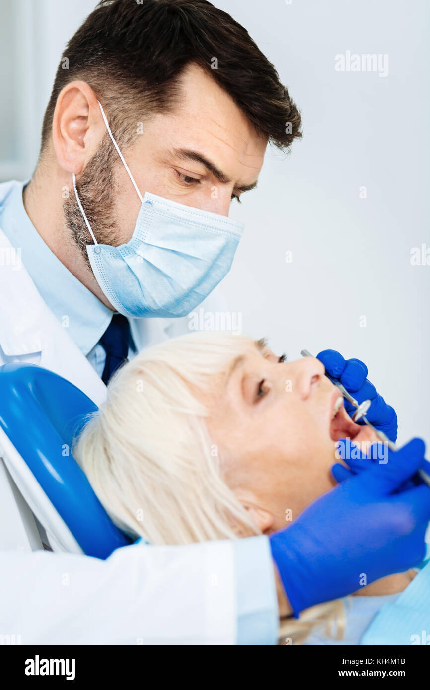 Concentrated dentist in the process of teeth curing Stock Photo - Alamy