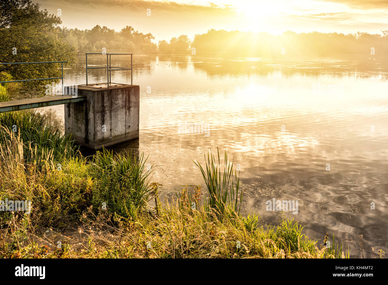 Small lake with floodgate under the golden sunset Stock Photo - Alamy