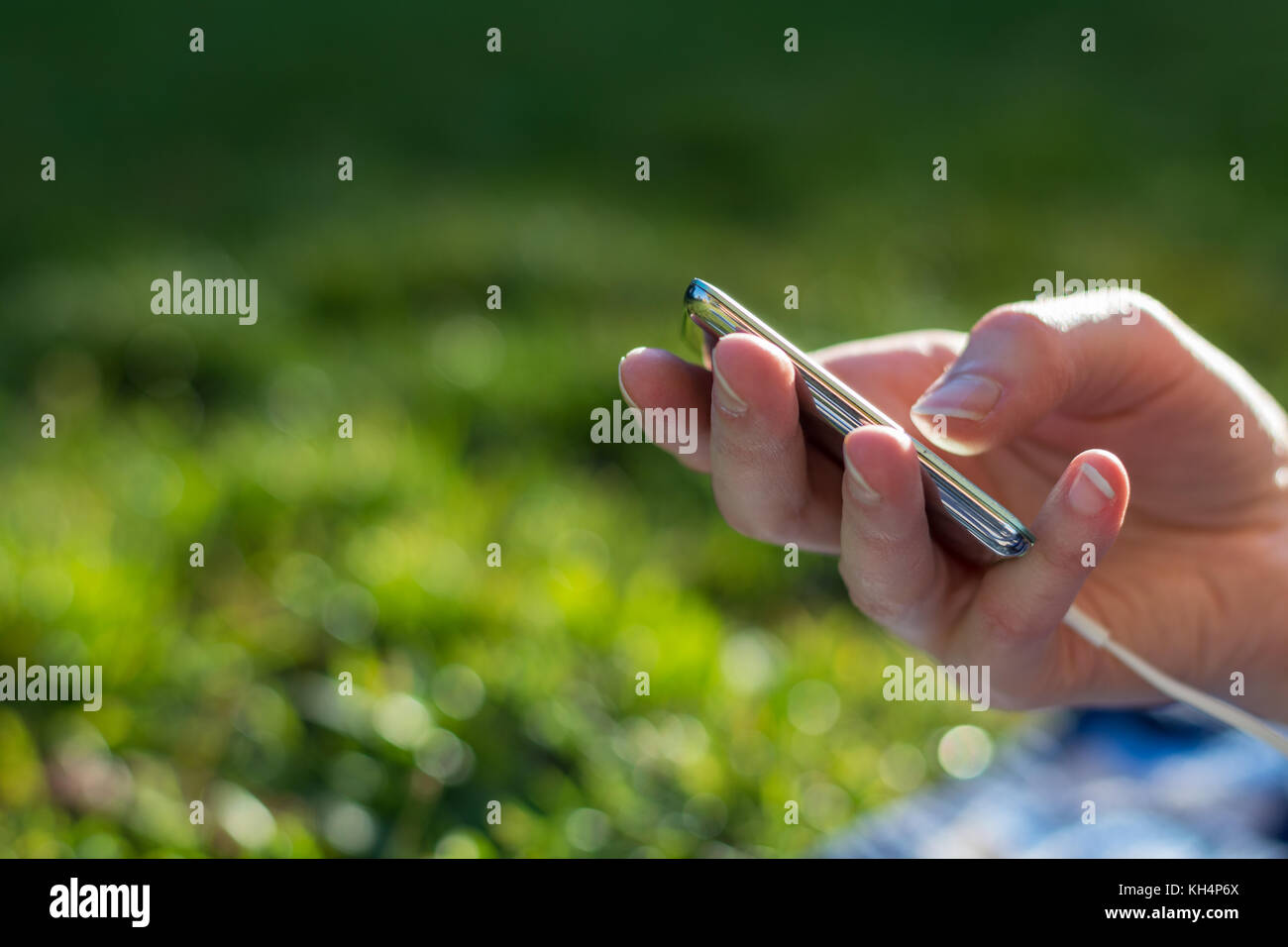 Holding an MP3 player in hand in a park with sunlight Stock Photo - Alamy