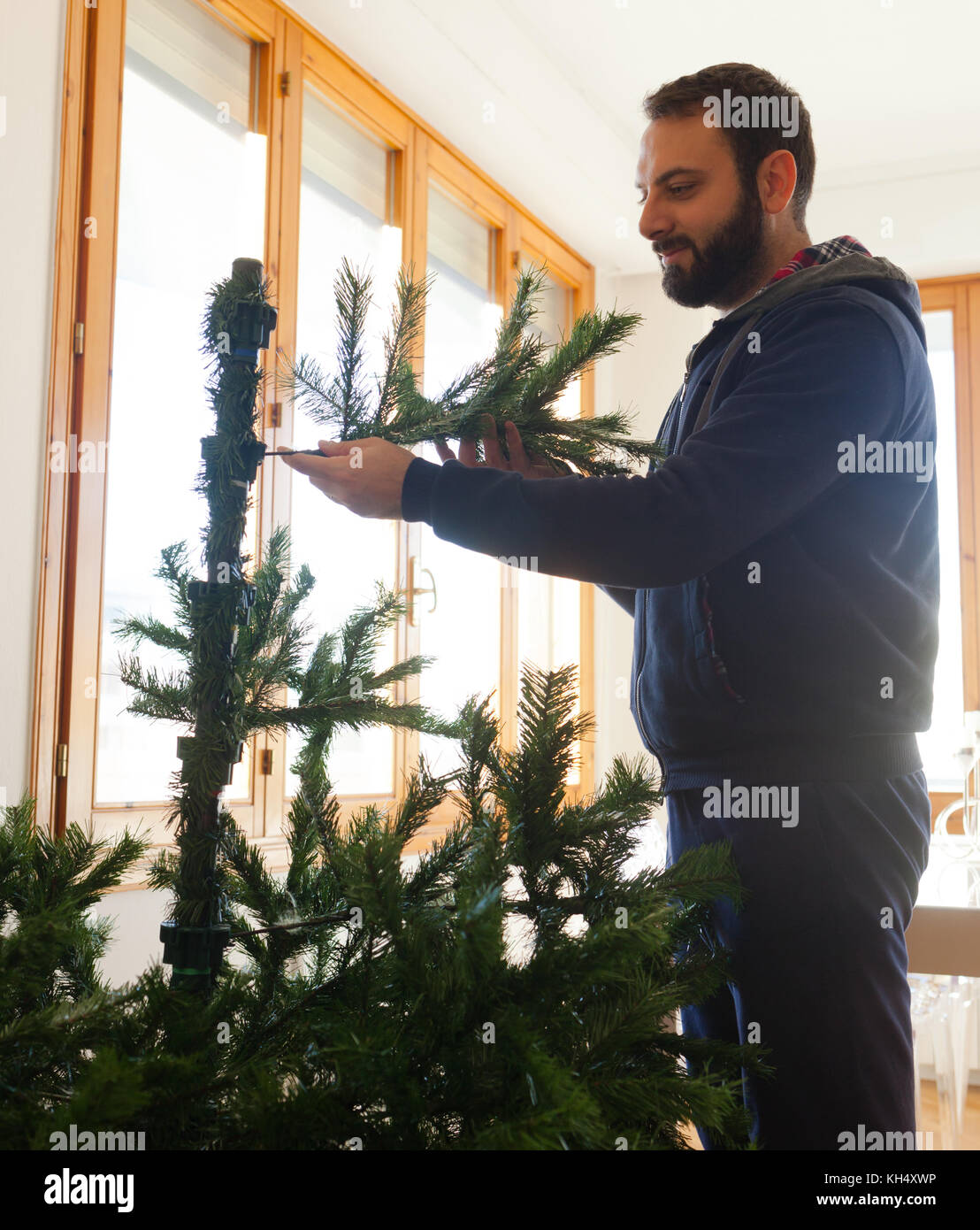 Young man mounting artificial Christmas tree. Each piece is placed ...