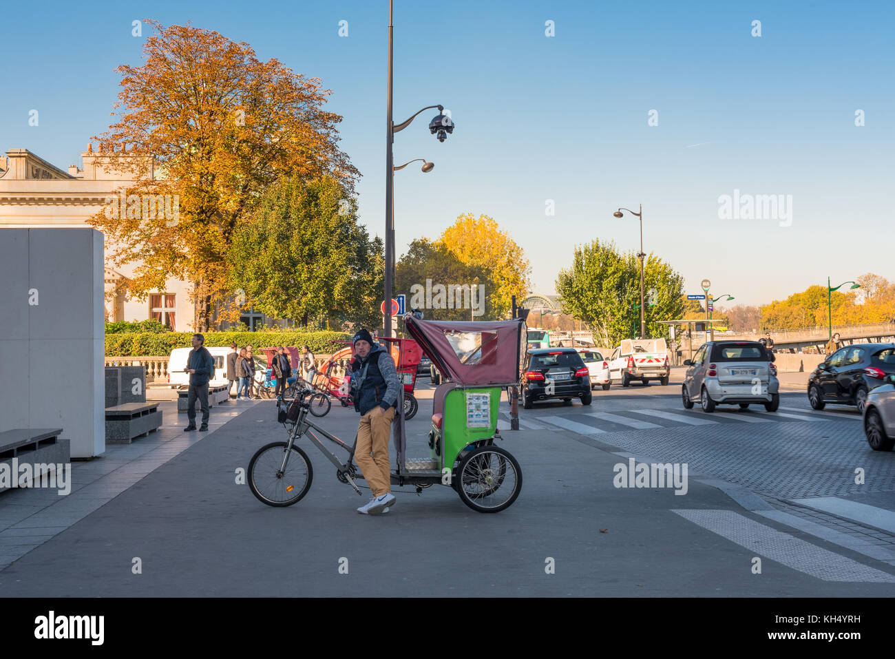 Paris, France -- November 7, 2017--A pedicab driver standing with his 3 ...