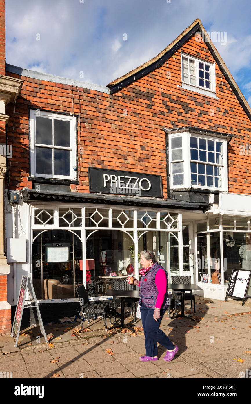 A woman carry a cup of coffee walks past Prezzo on Tenterden High ...