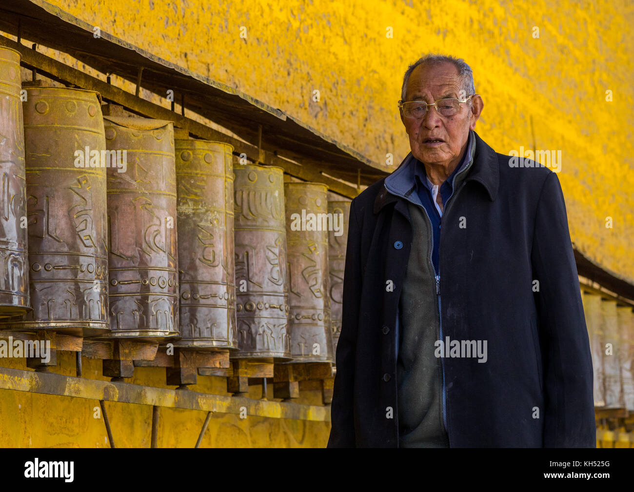 Tibetan pilgrim man turning huge prayer wheels in Rongwo monastery ...