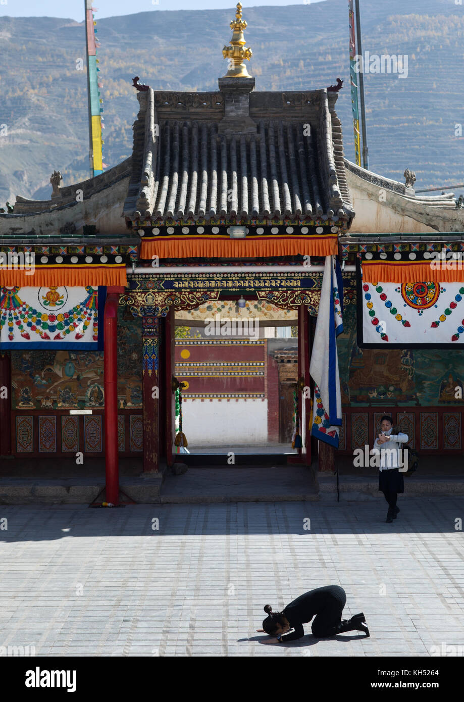 Tibetan woman praying in the middle of the temple courtyard in Rongwo ...