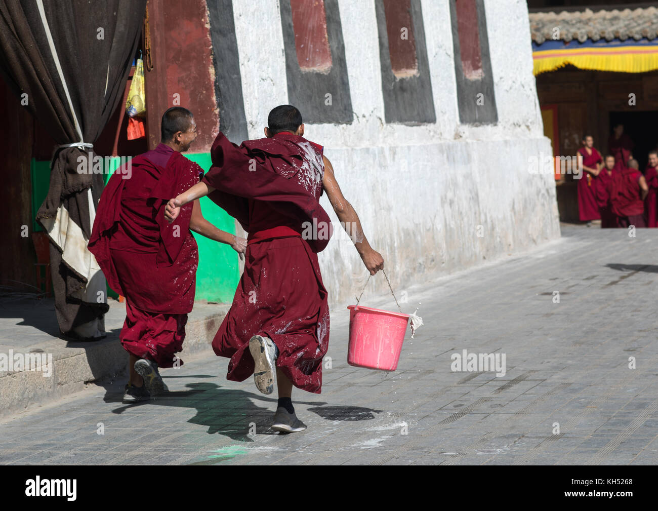 Monks carrying buckets for the painting of a temple in Rongwo monastery ...