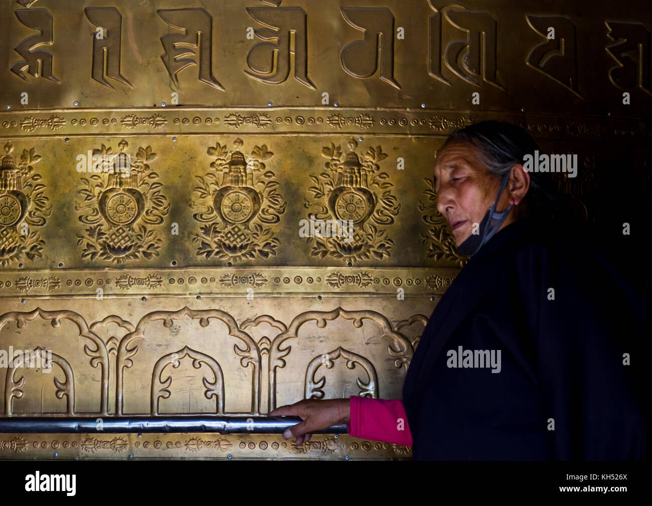 Tibetan pilgrim turning huge prayer wheel in Rongwo monastery, Tongren ...