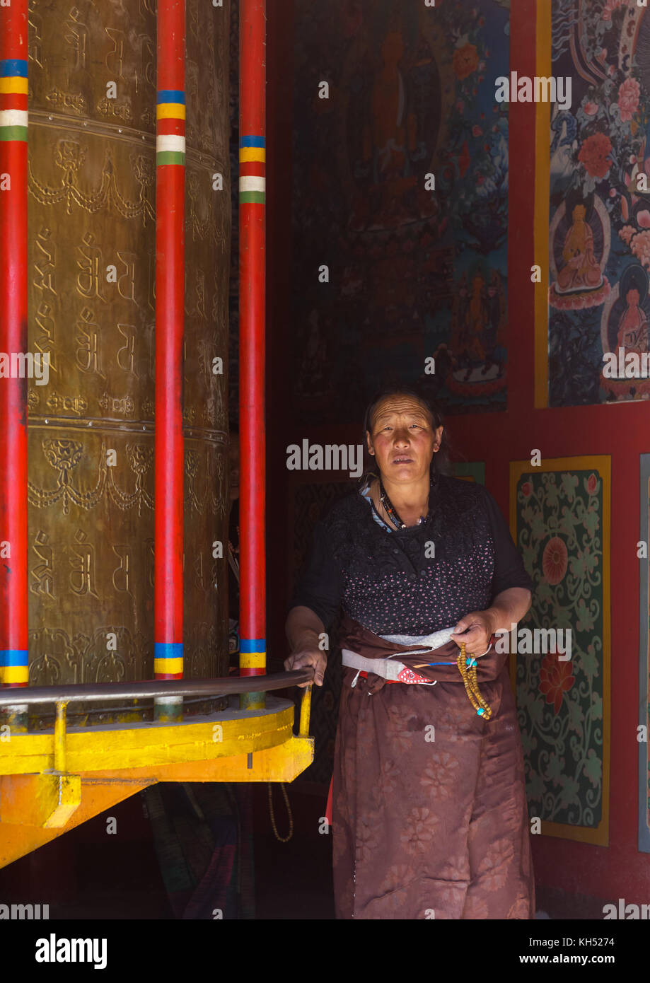 Tibetan woman turning prayer wheels in a Rongwo monastery, Tongren ...
