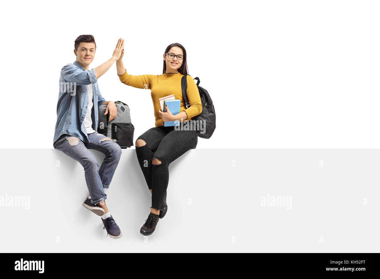 Teenage students seated on a panel high-fiving each other and looking ...