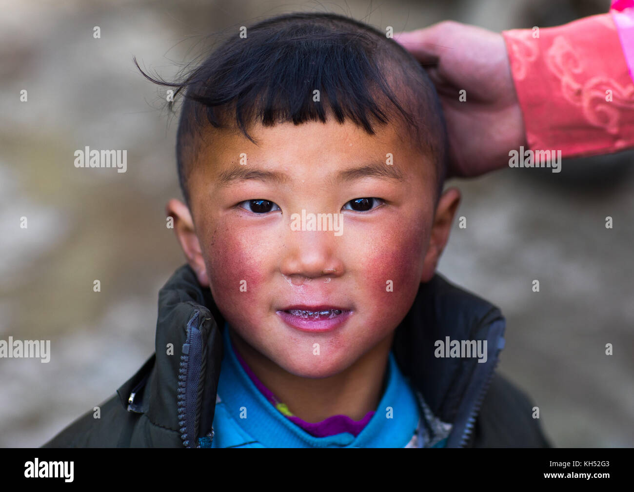 Portrait of a tibetan nomad child with his mother hand on his head ...
