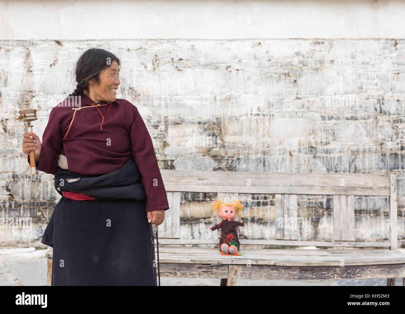 Tibetan nomad woman holding a prayer wheel in her hand, Gansu province ...