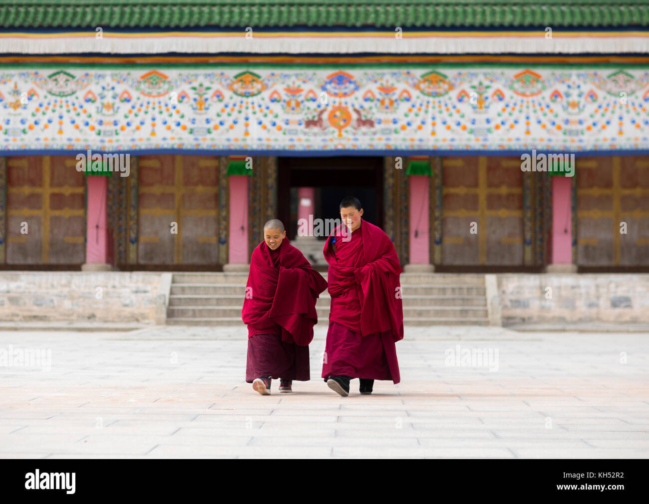 Tibetan monks coming out of a temple in Labrang monastery, Gansu ...
