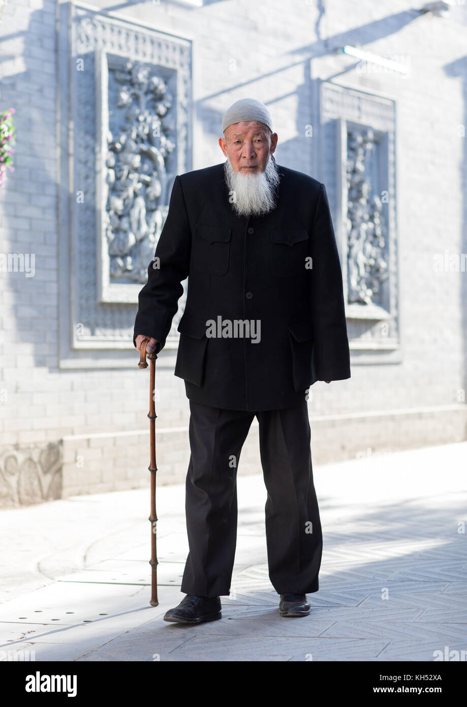 Hui muslim man walking with cane in the street, Gansu province, Linxia ...