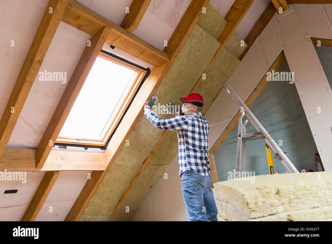 Man installing thermal roof insulation layer - using mineral wool ...