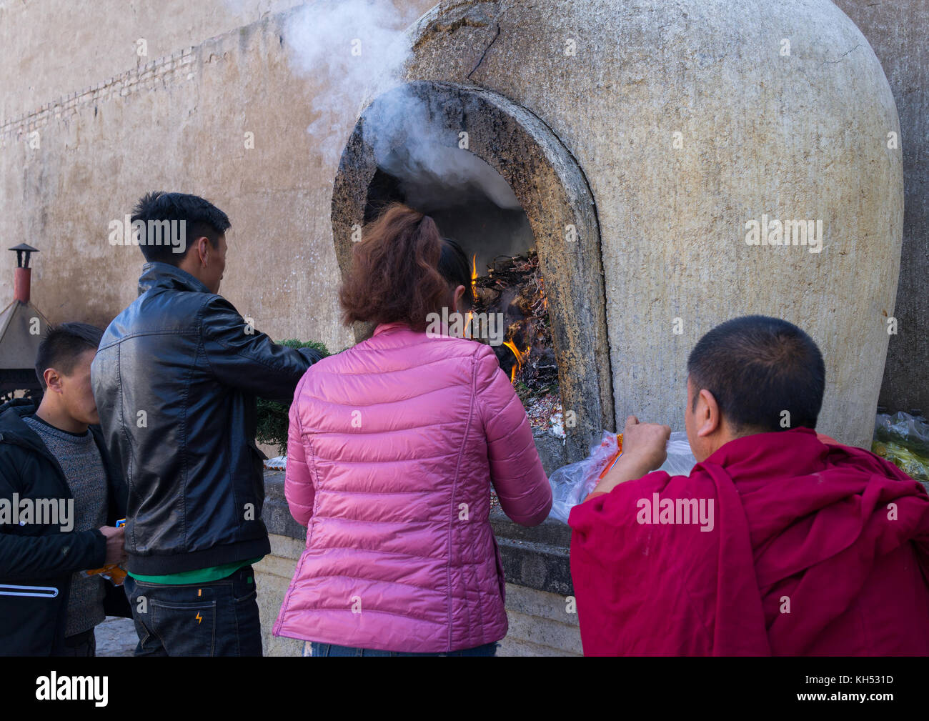 Tibetan pilgrims burning offerings in an oven in Rongwo monastery ...