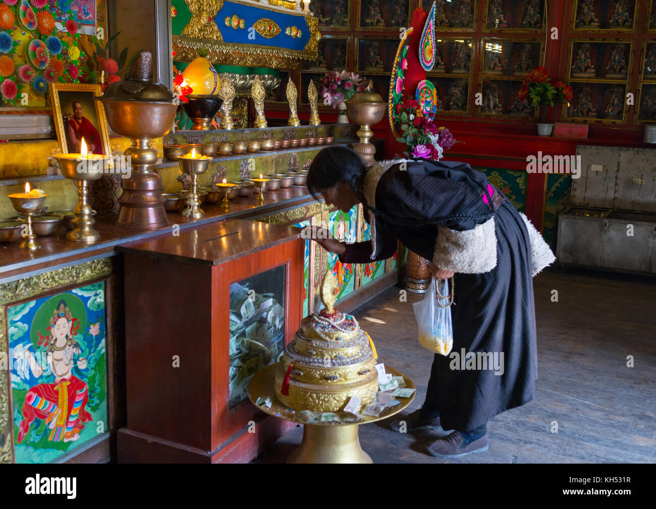 Tibetan woman praying inside a temple of Rongwo monastery, Tongren ...