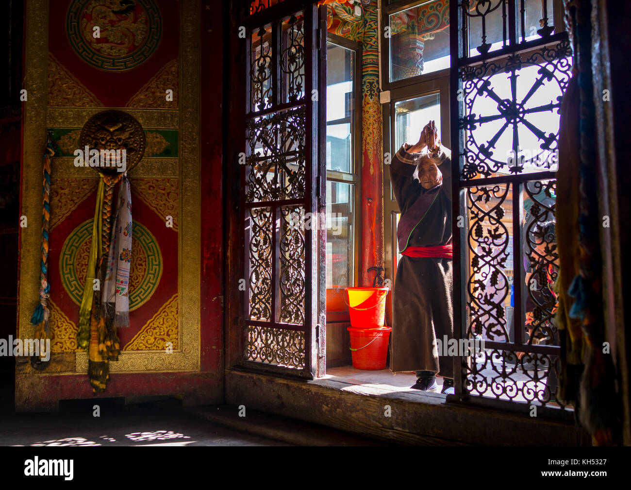Tibetan woman praying at the entrance of a temple in Rongwo monastery ...