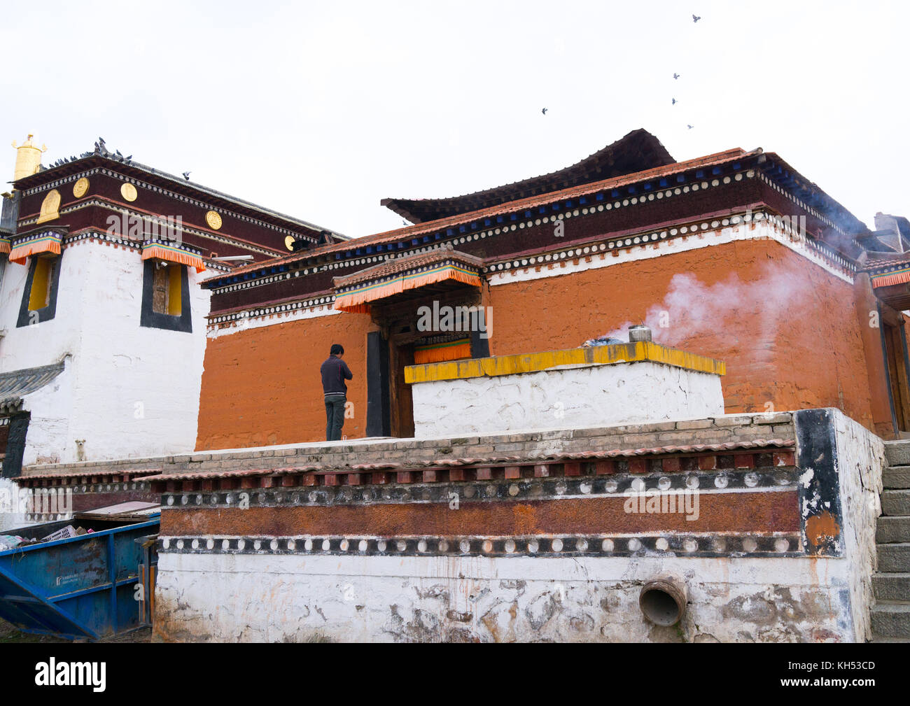 Tibetan man praying in front of a temple in Hezuo monastery, Gansu ...