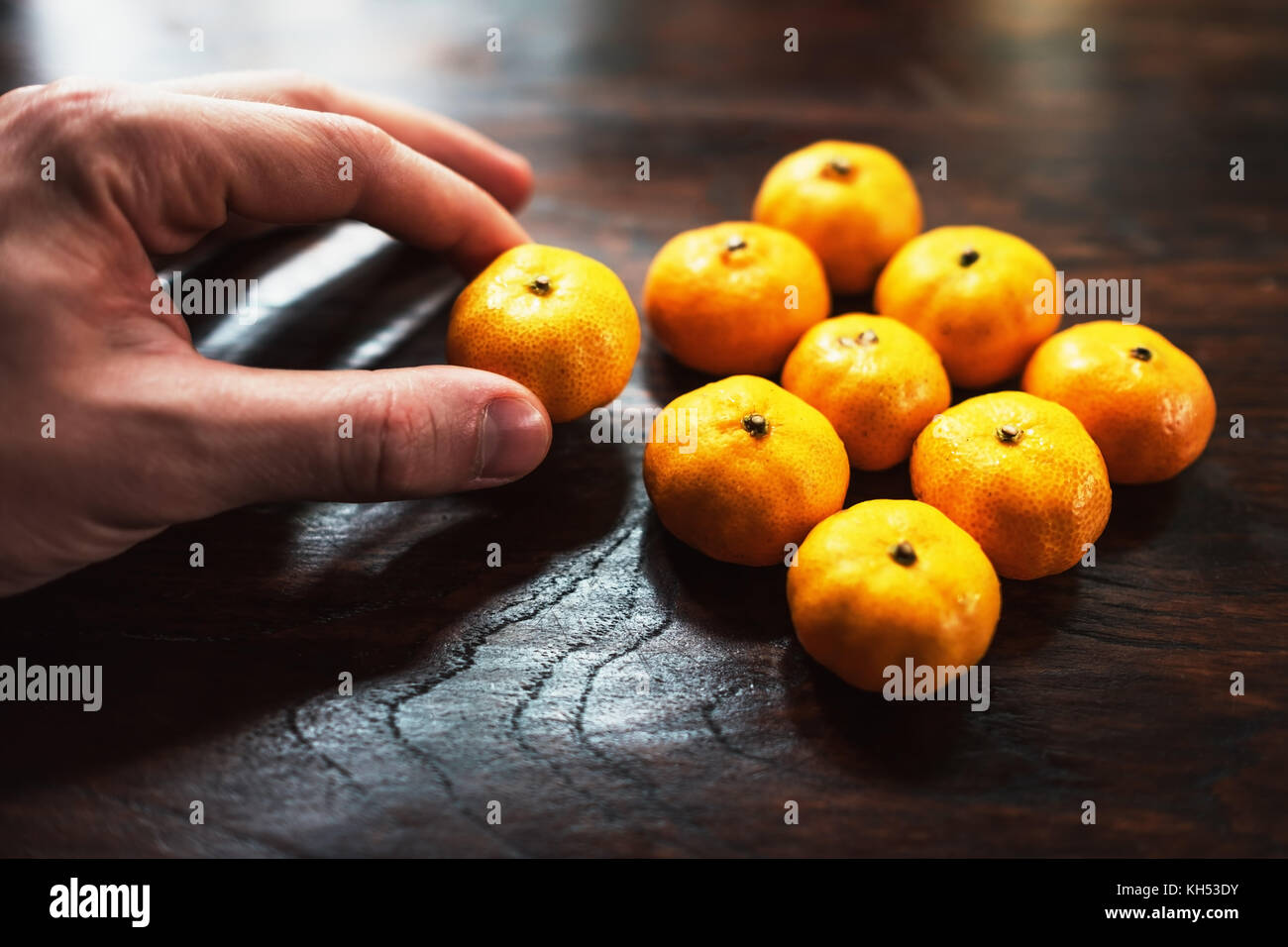 Hand holding mandarin on wooden table Stock Photo - Alamy