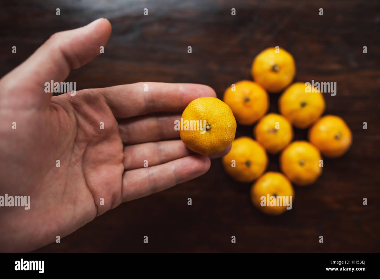 Hand holding mandarin on wooden table Stock Photo - Alamy