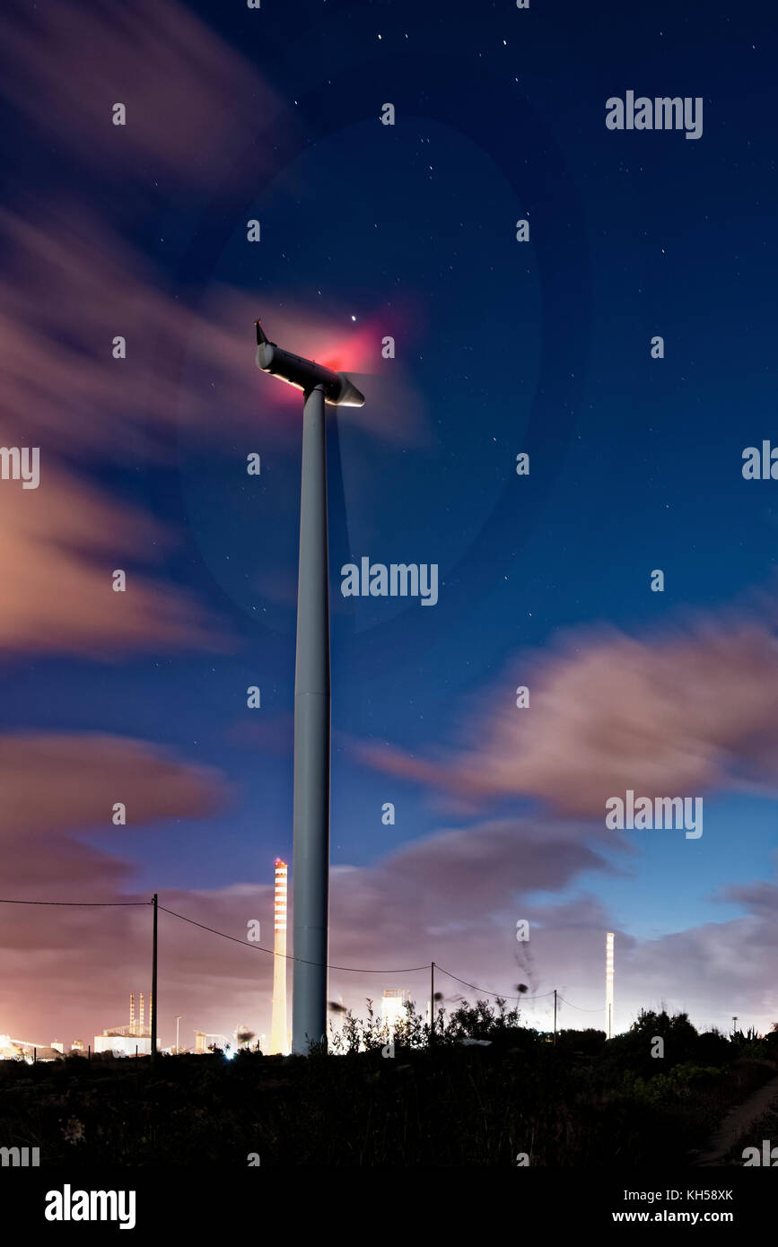 Windmill in the night with industries and cloudy sk Stock Photo - Alamy