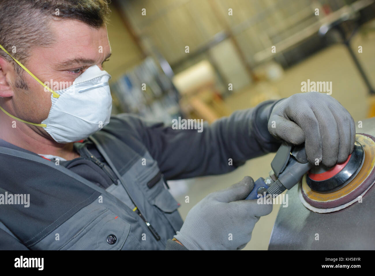 Masked man using sander Stock Photo - Alamy