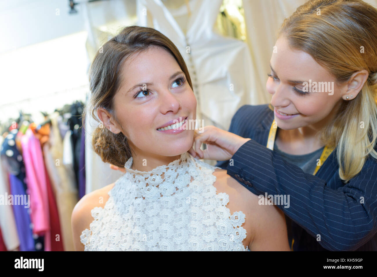 female trying wedding dress in a shop with women assistant Stock Photo ...
