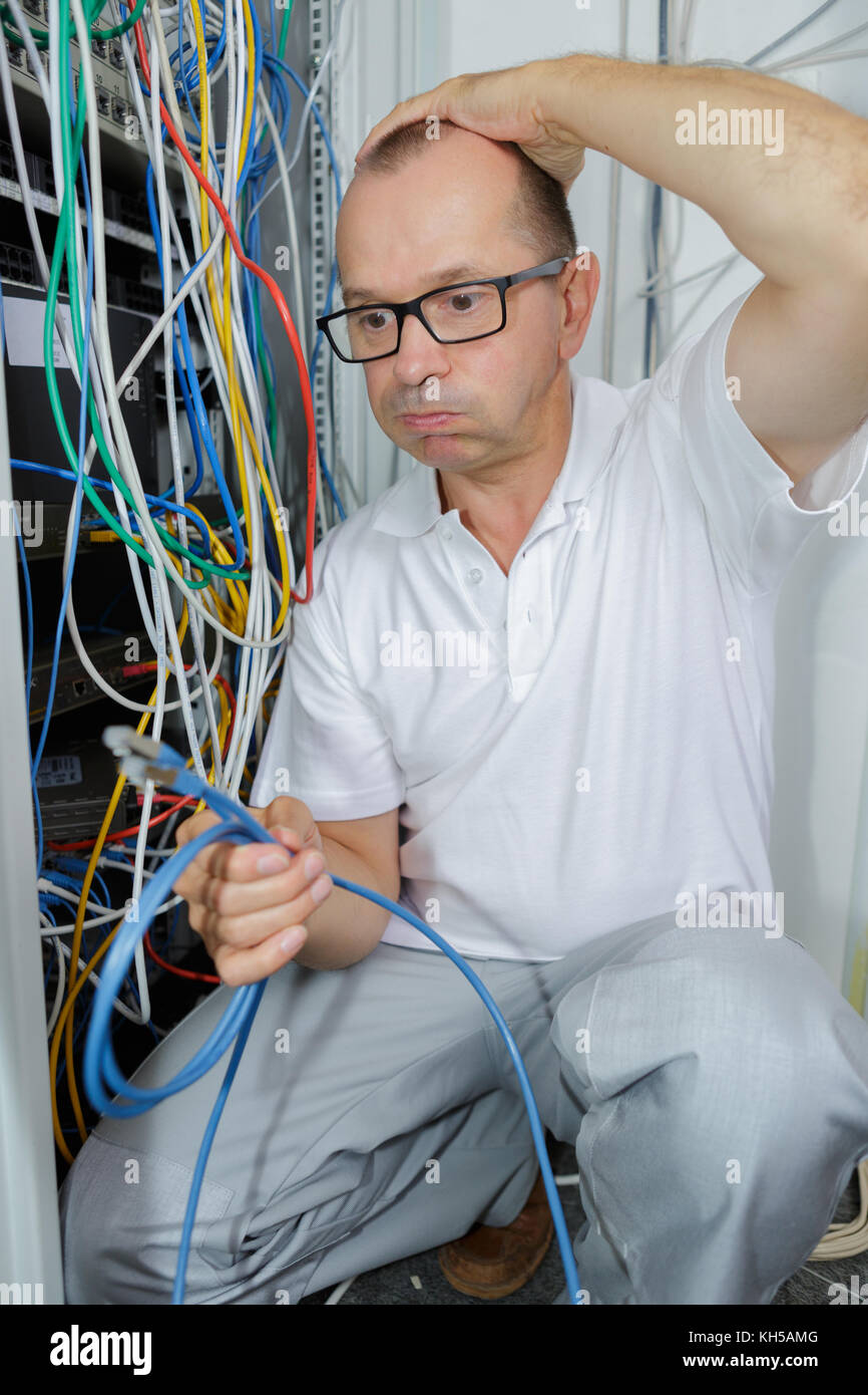 Confused man looking at cables Stock Photo - Alamy