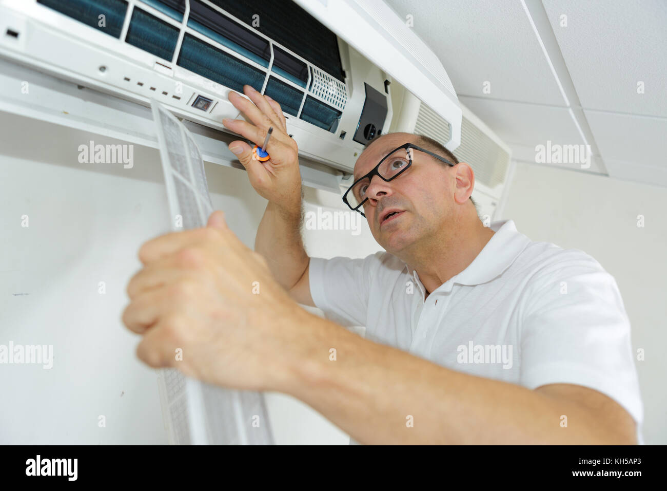 Man working on indoor air conditioning unit Stock Photo - Alamy
