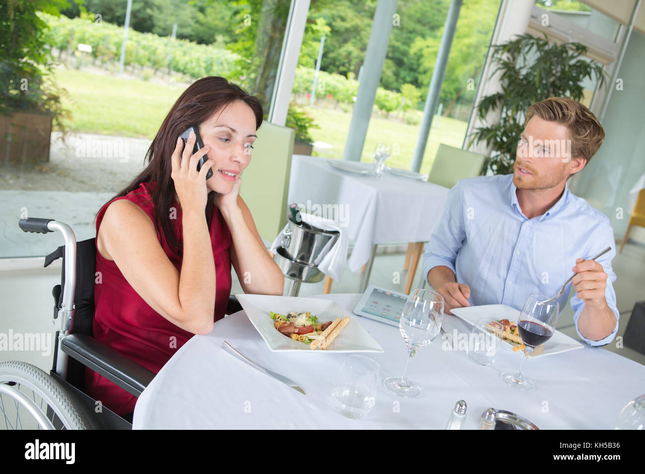 woman in a wheelchair talking on the phone while eating Stock Photo - Alamy