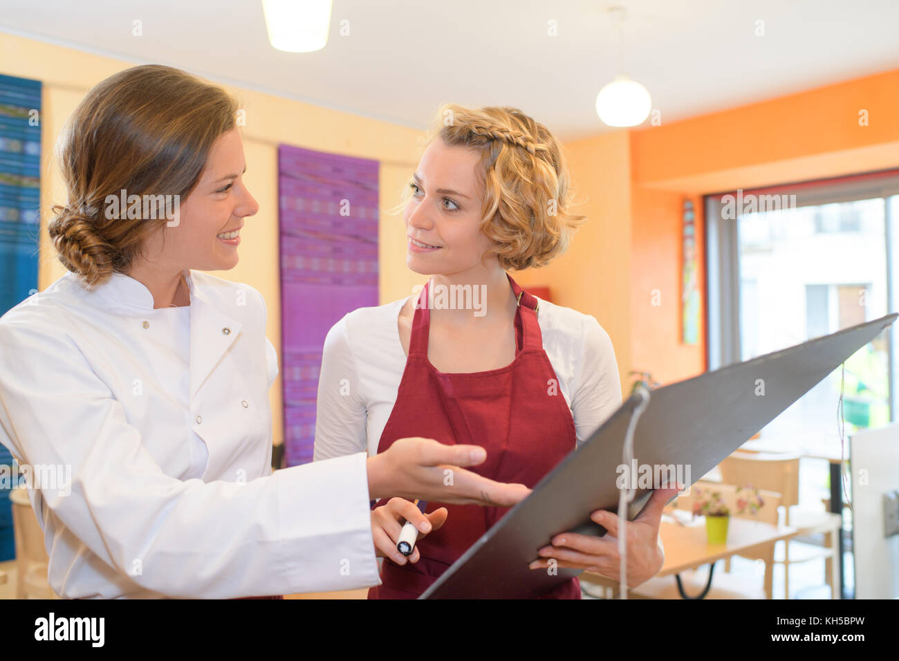 pretty female chef and waitress discussing the menu Stock Photo - Alamy