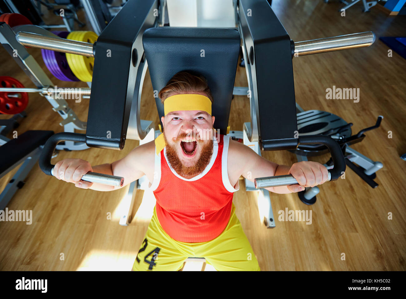 A fat man is doing exercises on the simulator in the gym Stock Photo ...