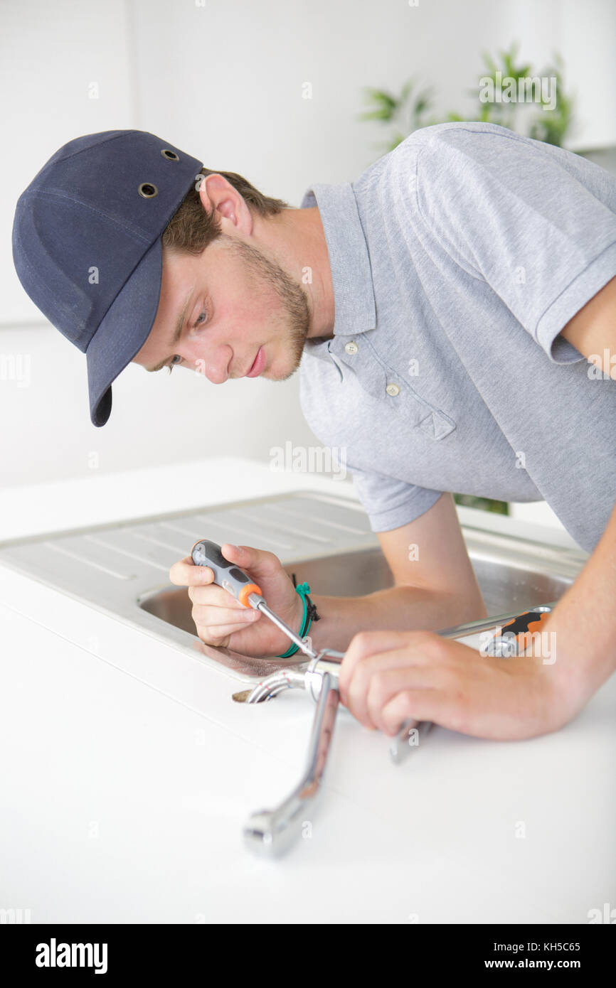 happy young man fixing tap in the kitchen Stock Photo - Alamy