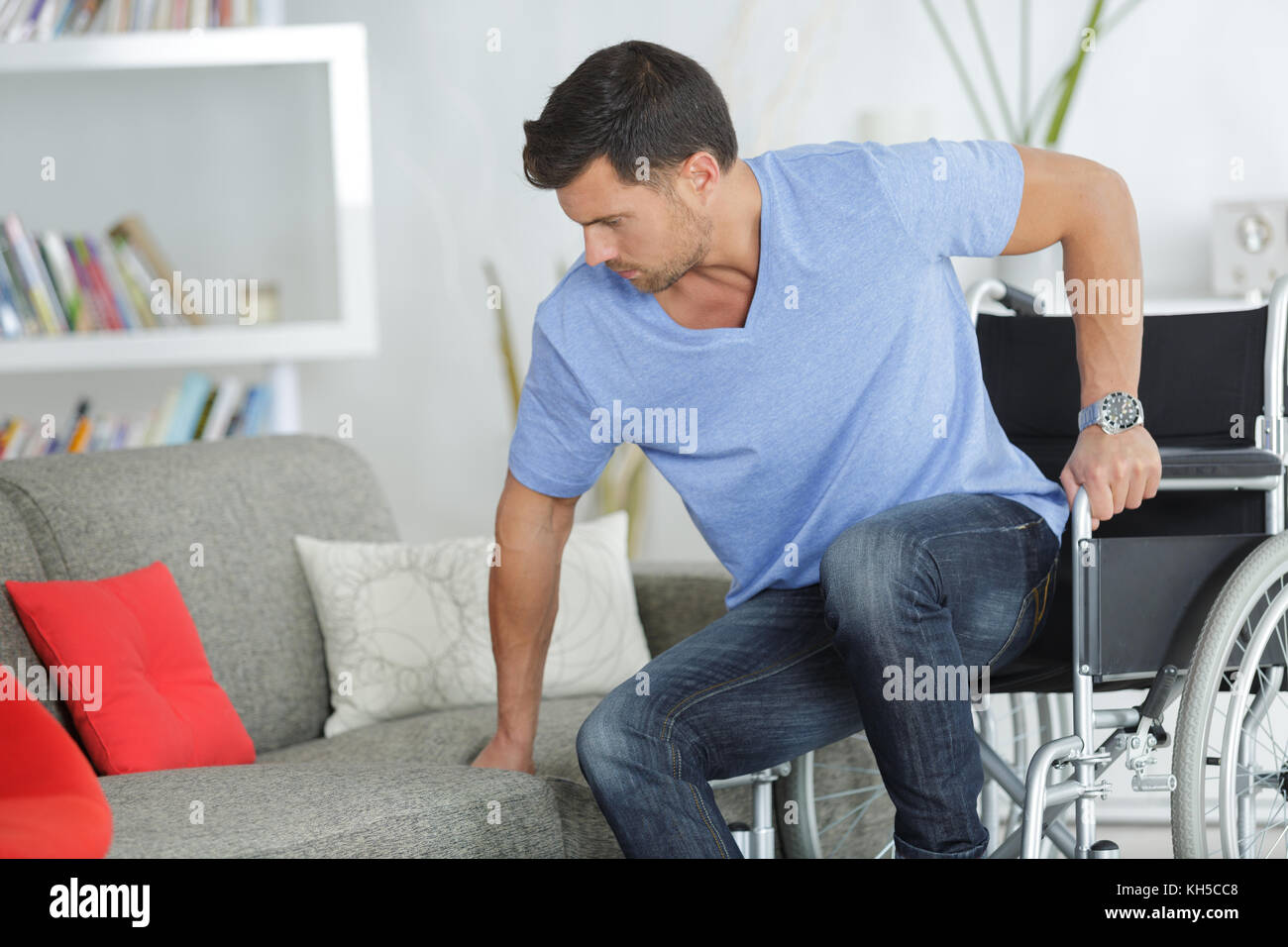 disabled man trying to sit on a couch Stock Photo - Alamy