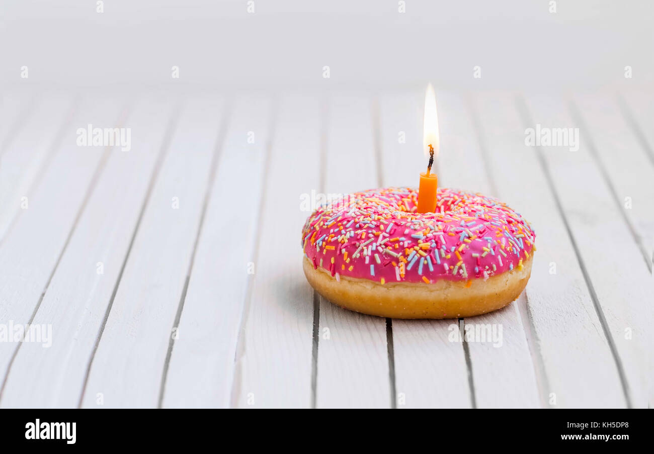 Birthday donut with pink glaze and colorful candies and burning candle , birthday concept Stock ...