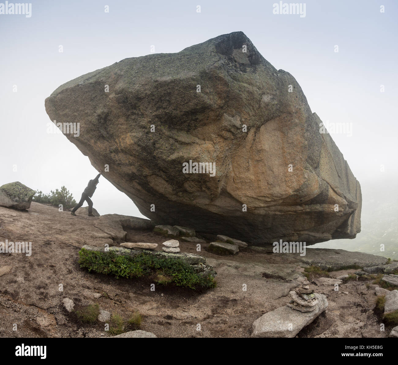 Man with pushing a huge stone in Ergaki mountains, Russia Stock Photo ...