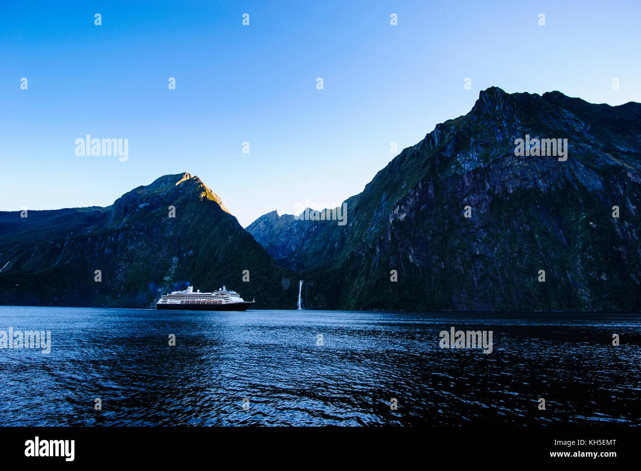 Cruise ship passing a waterfall in Milford Sound, South Island, New ...