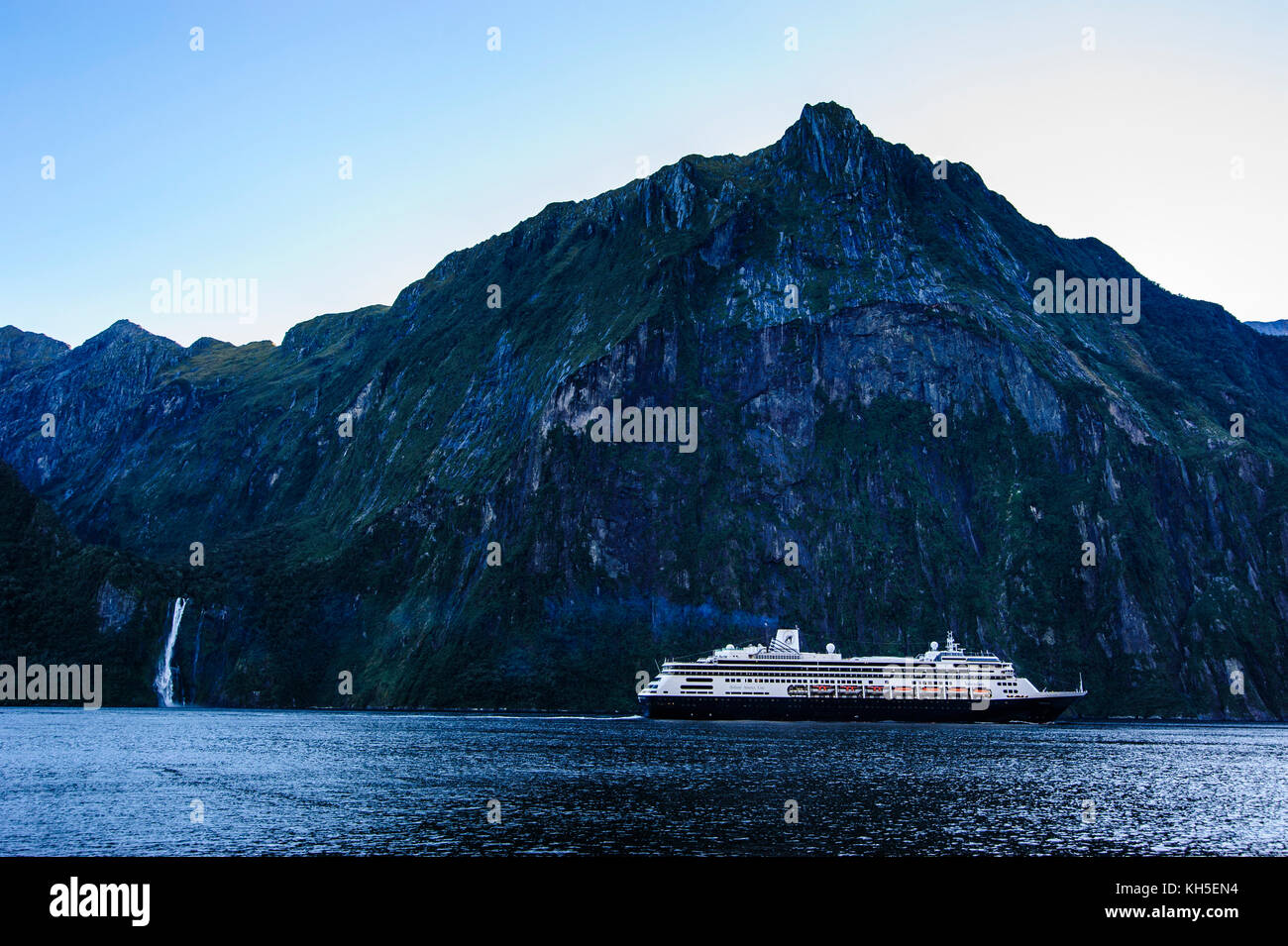 Cruise ship passing a waterfall in Milford Sound, South Island, New ...