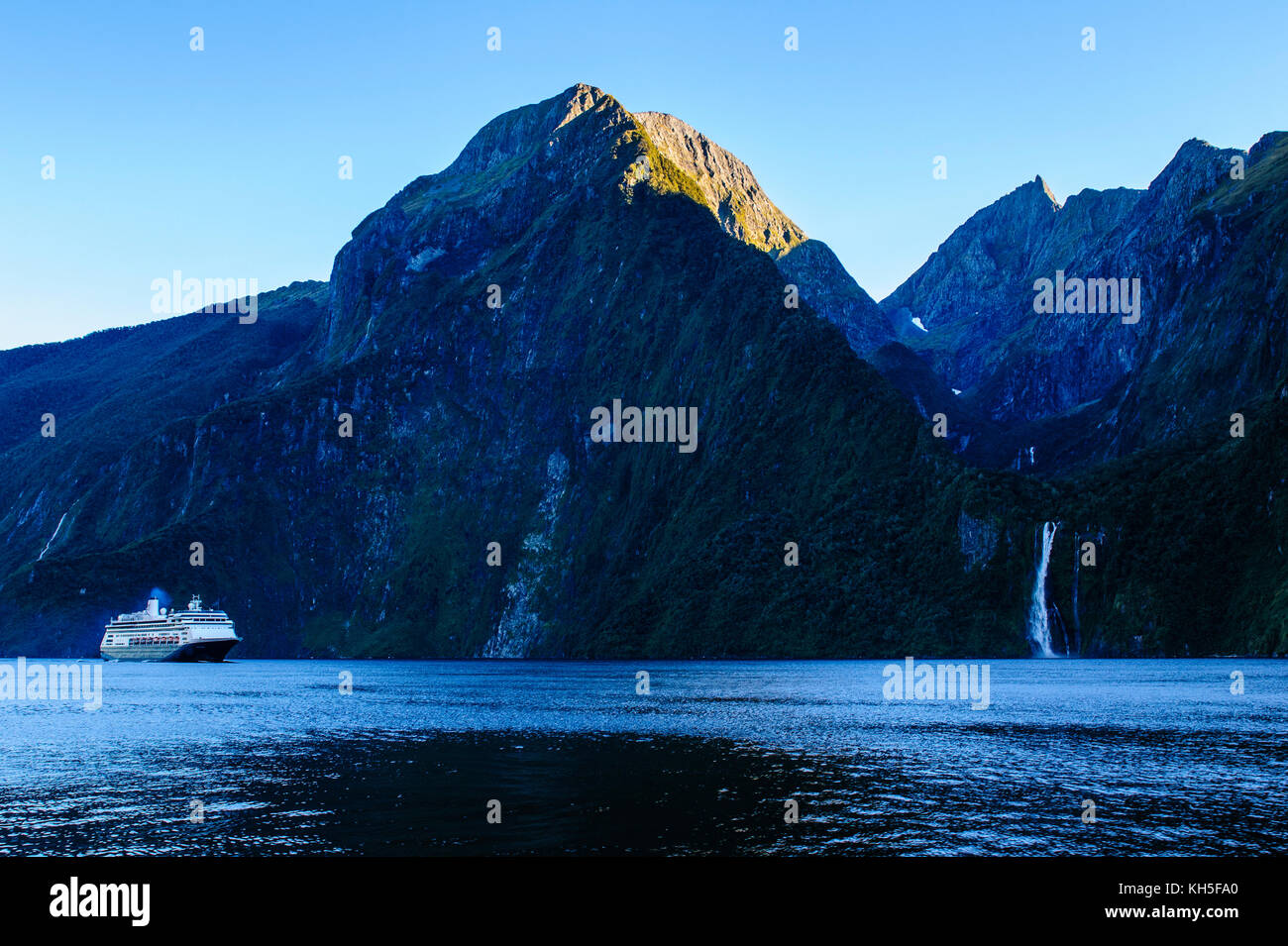 Cruise ship passing a waterfall in Milford Sound, South Island, New ...