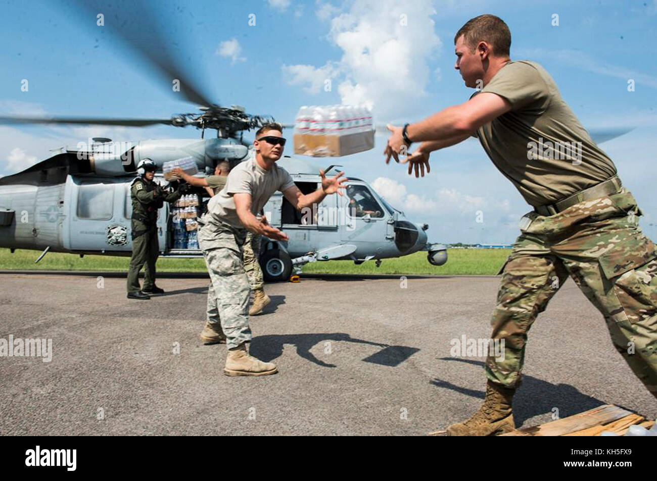 U.S. Soldiers and Sailors load water onto a U.S. Navy MH-60S Sea Hawk ...