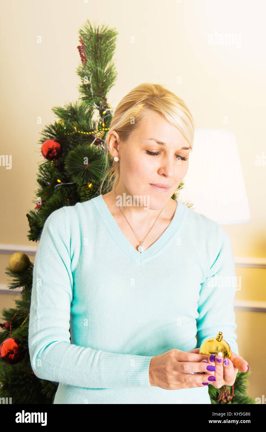Woman sitting near a Christmas tree with bauble in hands Stock Photo ...