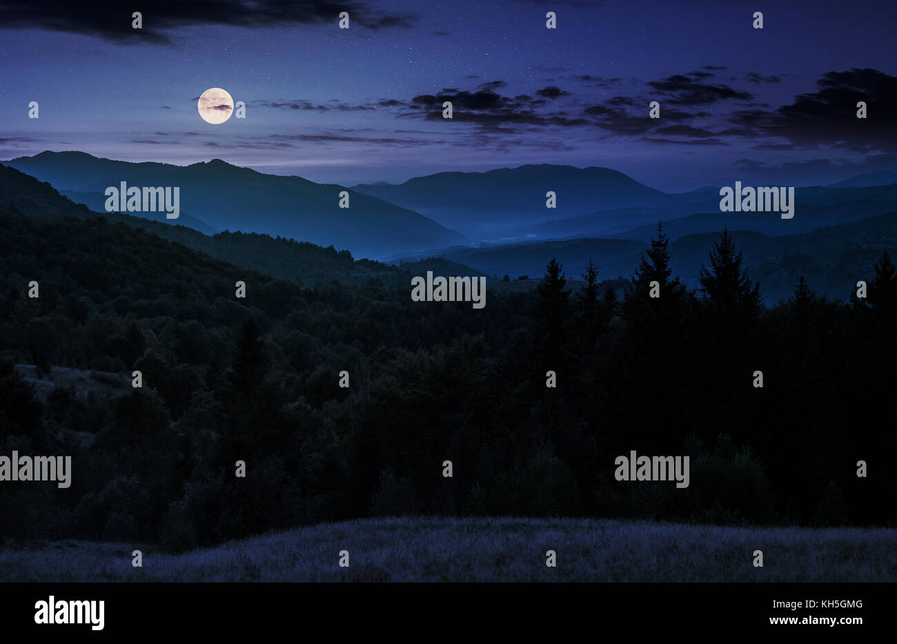 full moon rise above forested mountain at night. gorgeous Carpathian ...