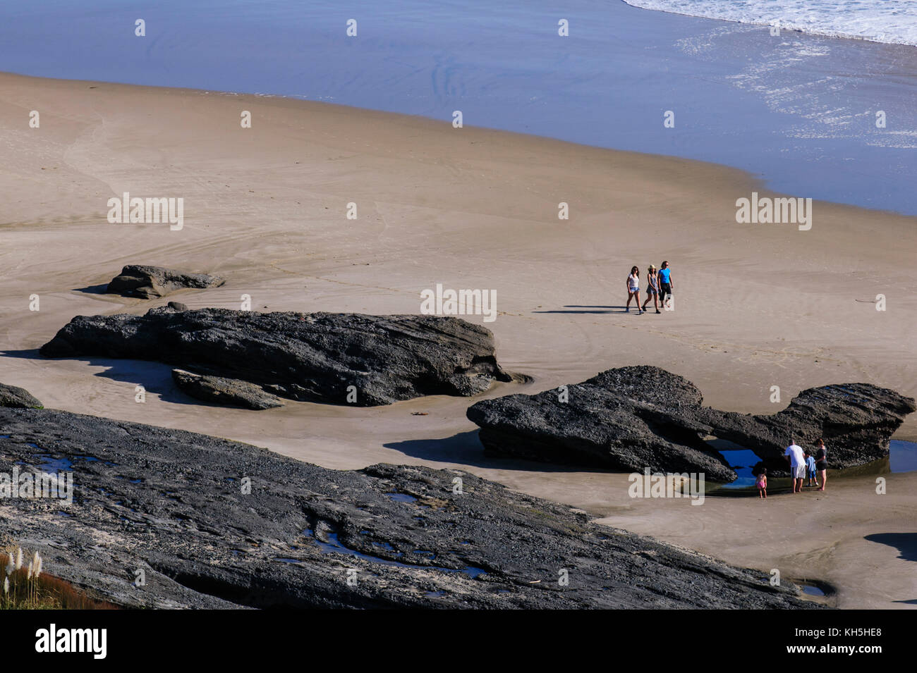 People walking on a beach with huge rocks, Arai-Te-Uru Recreation ...