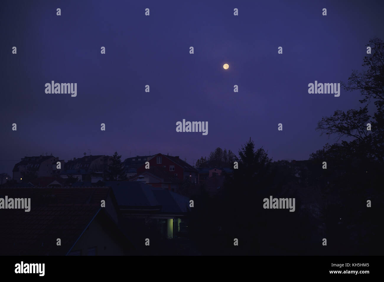 Late night scene with clear moon and roofs of houses and buildings of ...