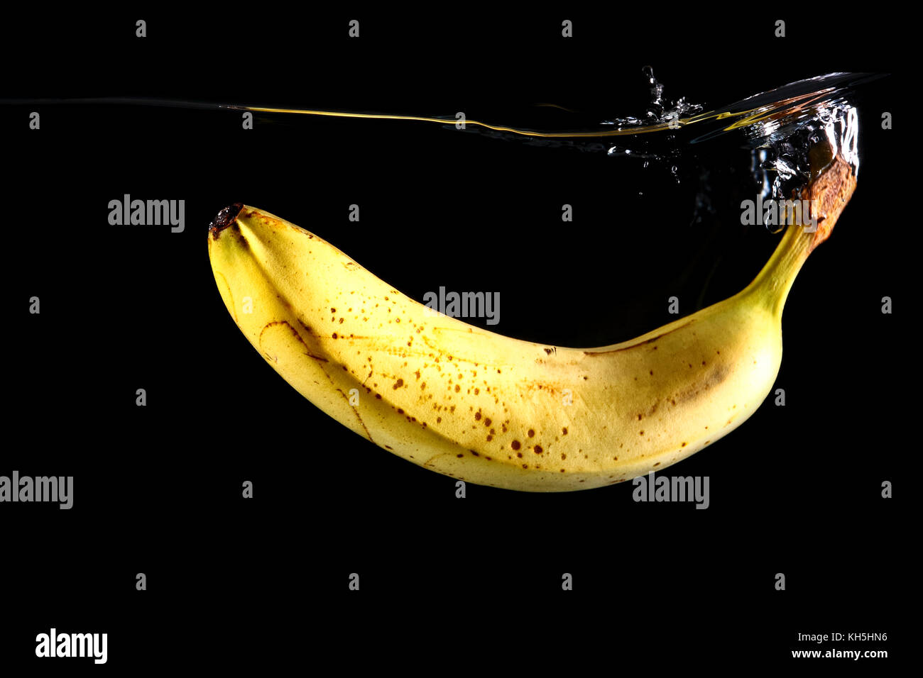 Close up of a banana falling in to water isolated on a black background ...