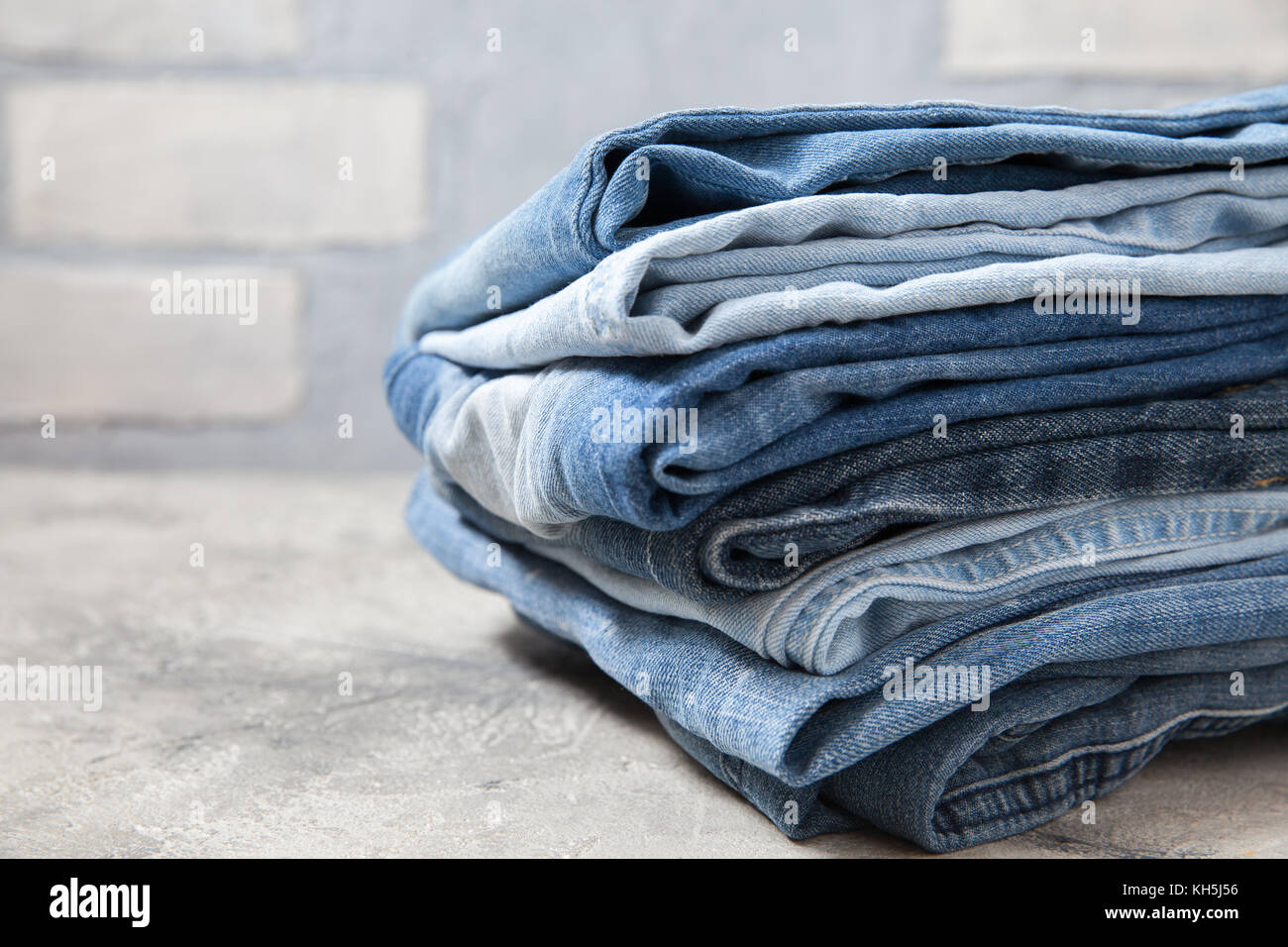 stack of blue jeans on a gray background Stock Photo - Alamy