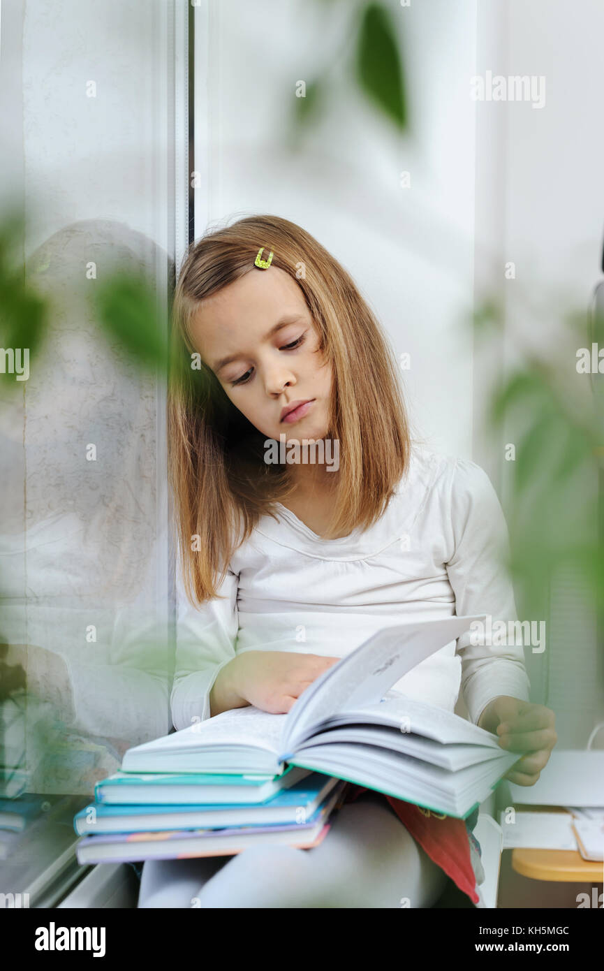 The girl is sitting on the window sill and reading a book Stock Photo ...