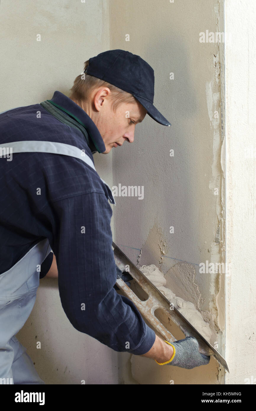 Man gets manually gypsum plaster on the wall Stock Photo - Alamy