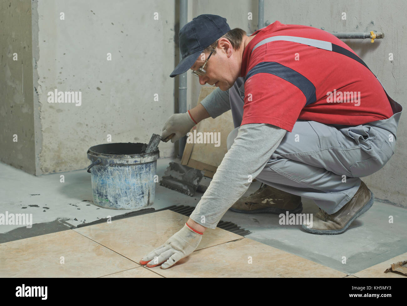 Laying Ceramic Tiles. Tiler placing ceramic floor tile in position over ...